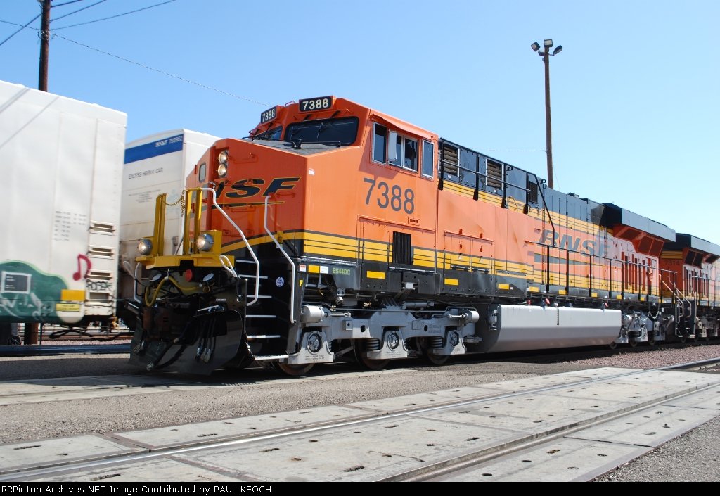 BNSF 7388 waits to roll west with a new crew as another train passes by on Main track 1 at the ...